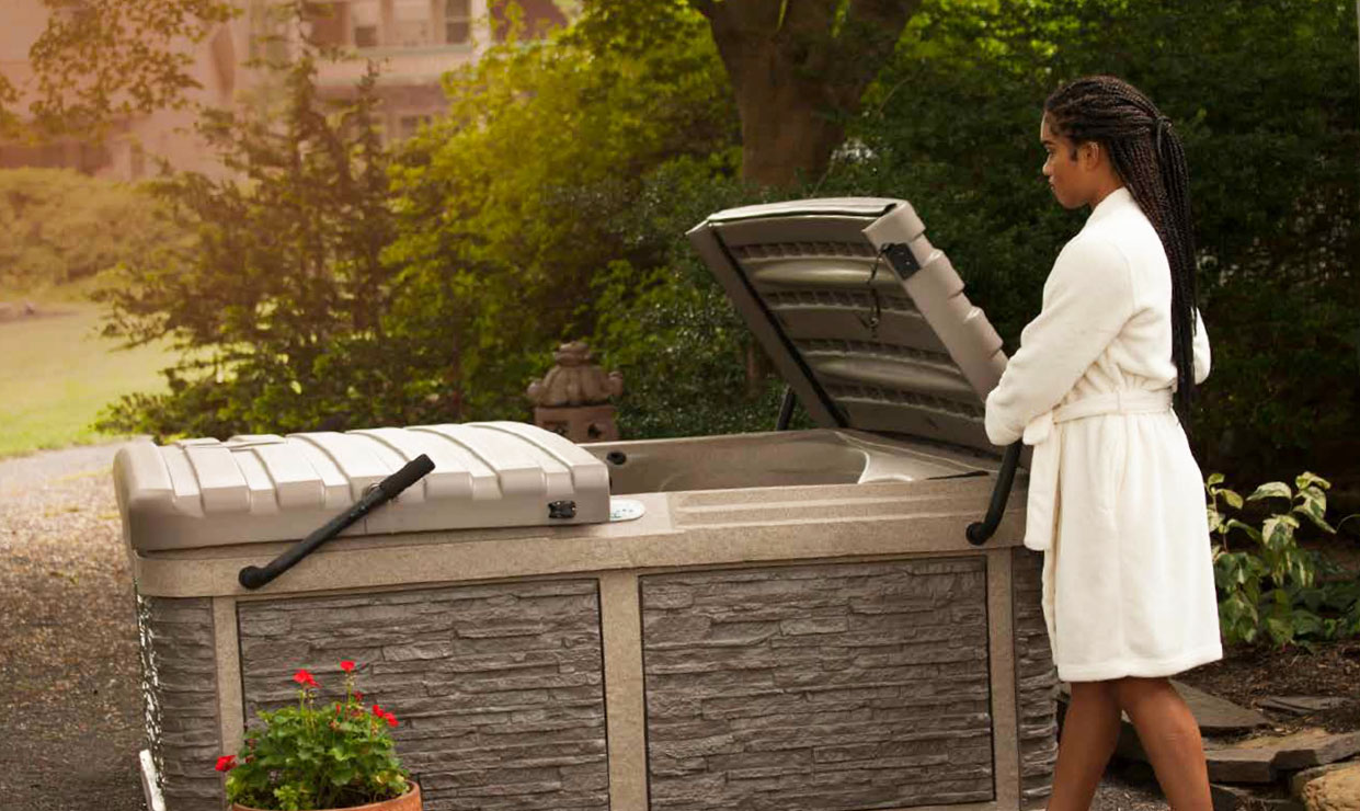 A young woman opens the top cover on her Strong Spa | Custom Spas Direct